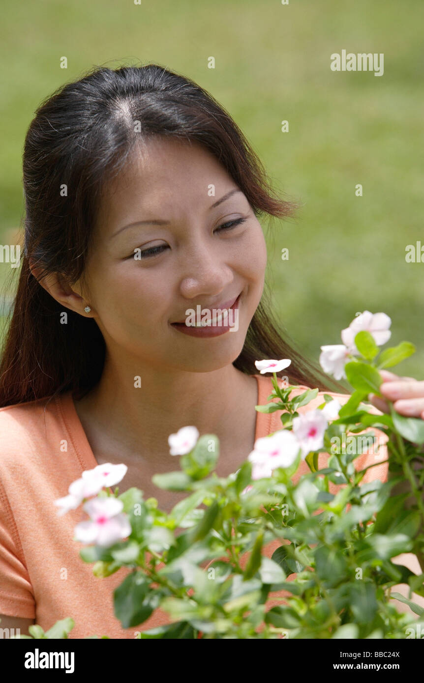 Woman outdoors, looking at flowering plants Stock Photo - Alamy