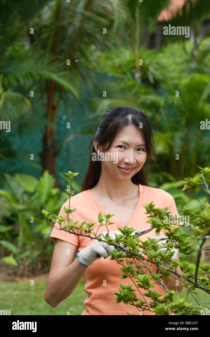 Woman in garden, pruning plant, smiling at camera Stock Photo - Alamy