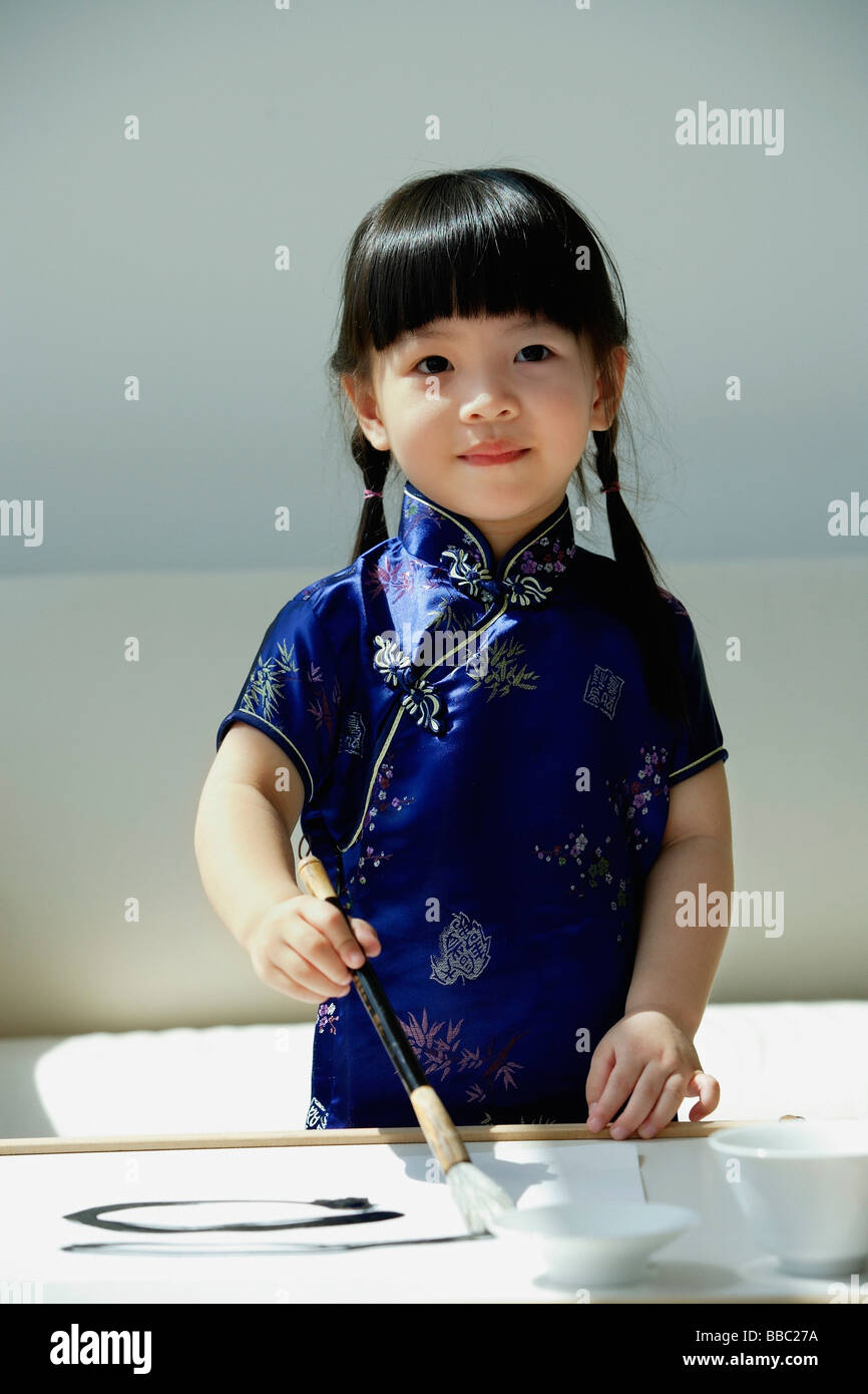 A small girl in blue silk cheongsam writing Chinese calligraphy Stock ...