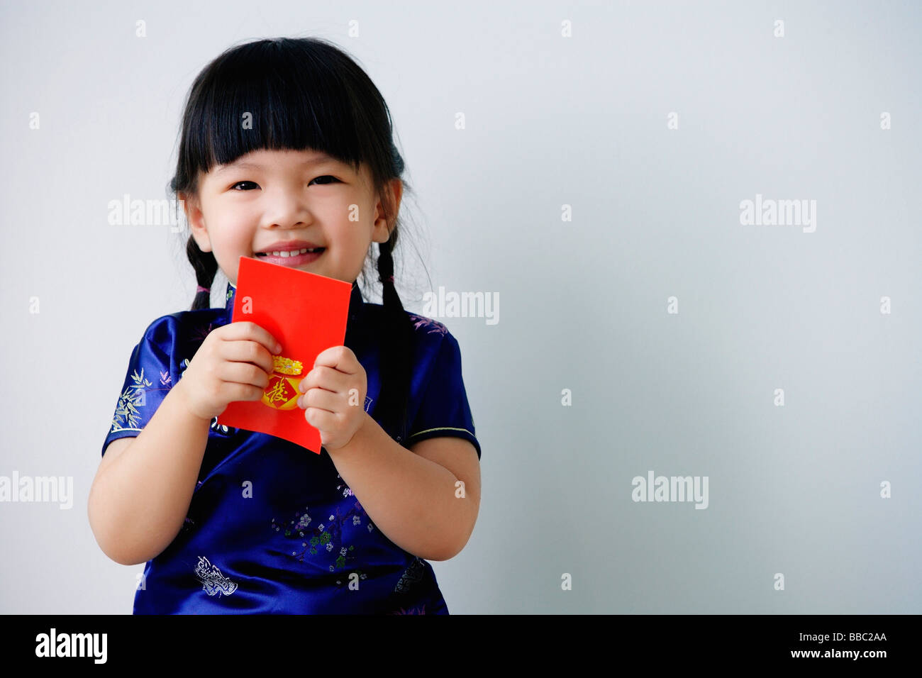 A small girl holds a red packet as she looks at the camera Stock Photo ...