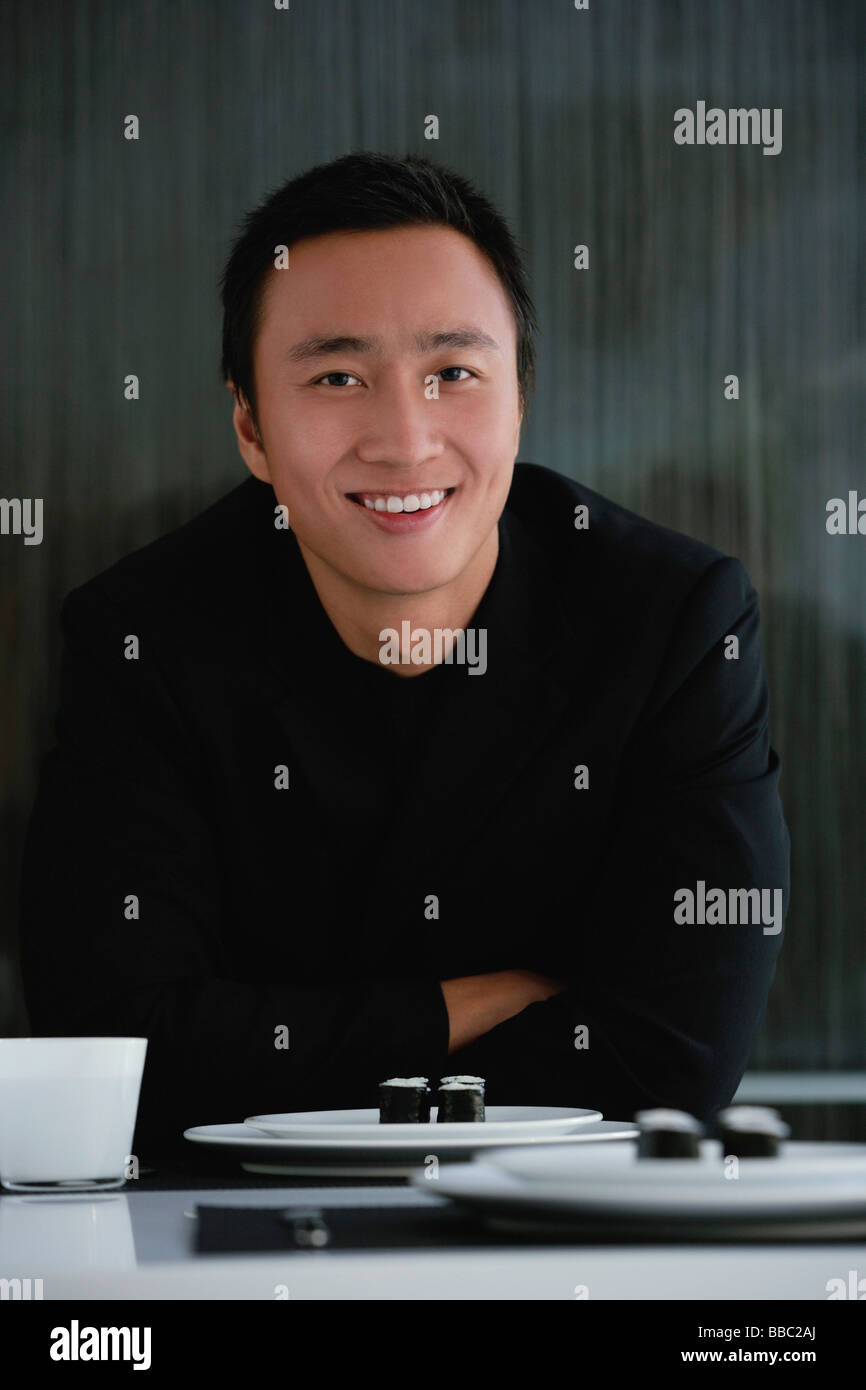 A man smiles at the camera while he sits at the table Stock Photo - Alamy
