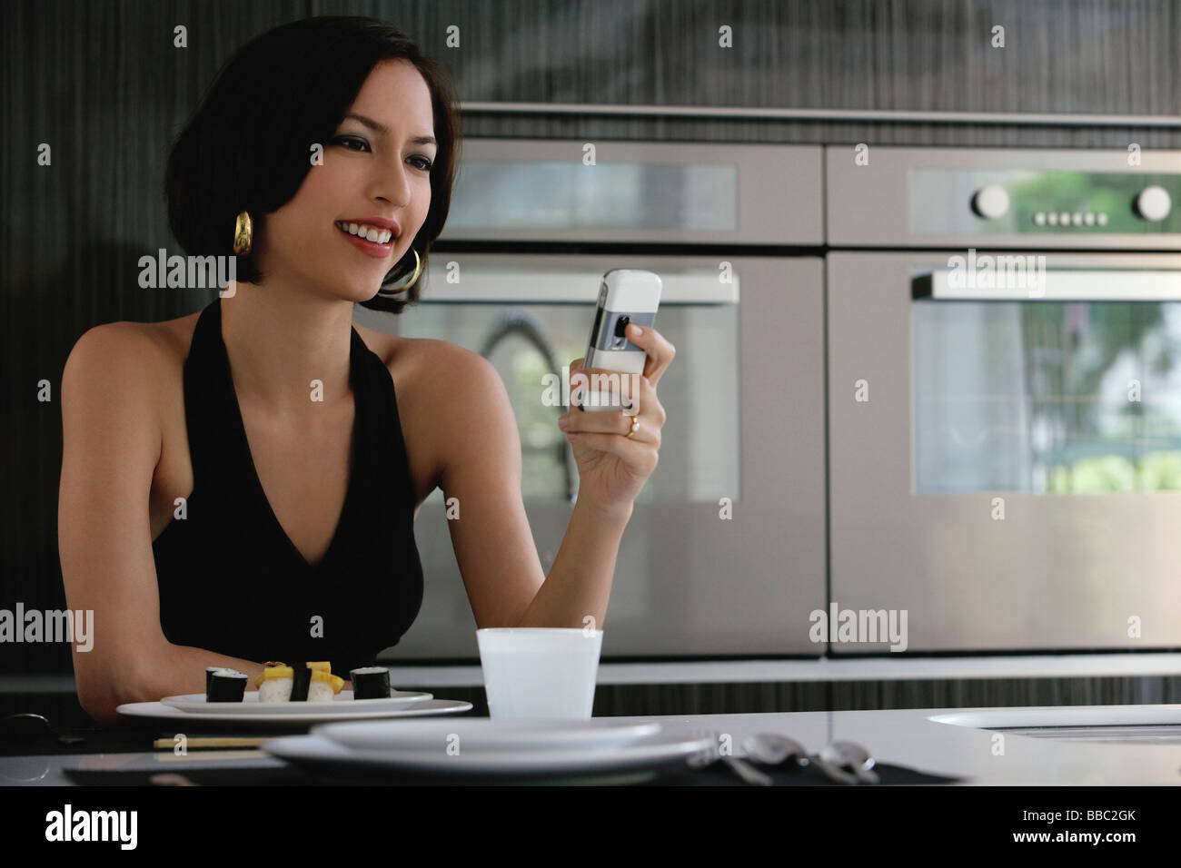 A woman checks her cellphone as she has dinner Stock Photo - Alamy