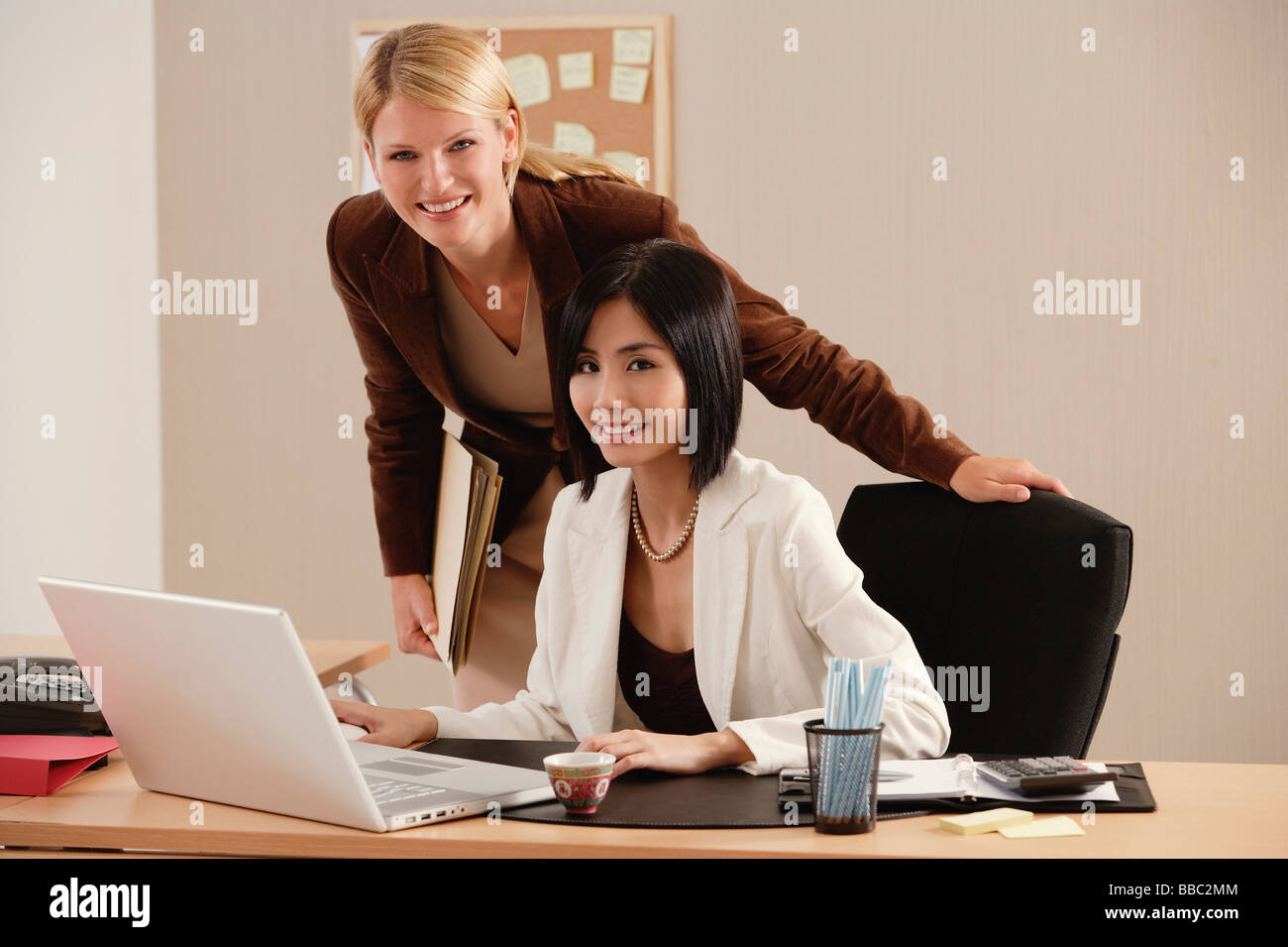 Two female colleagues smile at the camera together Stock Photo - Alamy