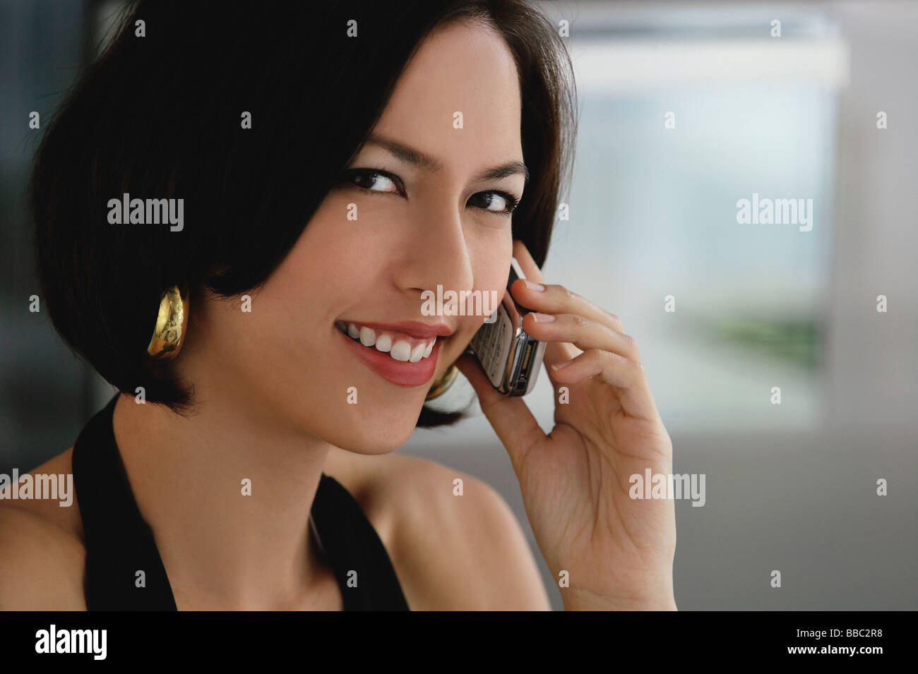 A woman smiles at the camera as she talks on her cellphone Stock Photo ...