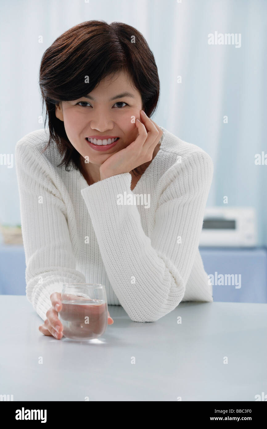 Woman leaning in table, holding glass, hand on chin, portrait Stock ...