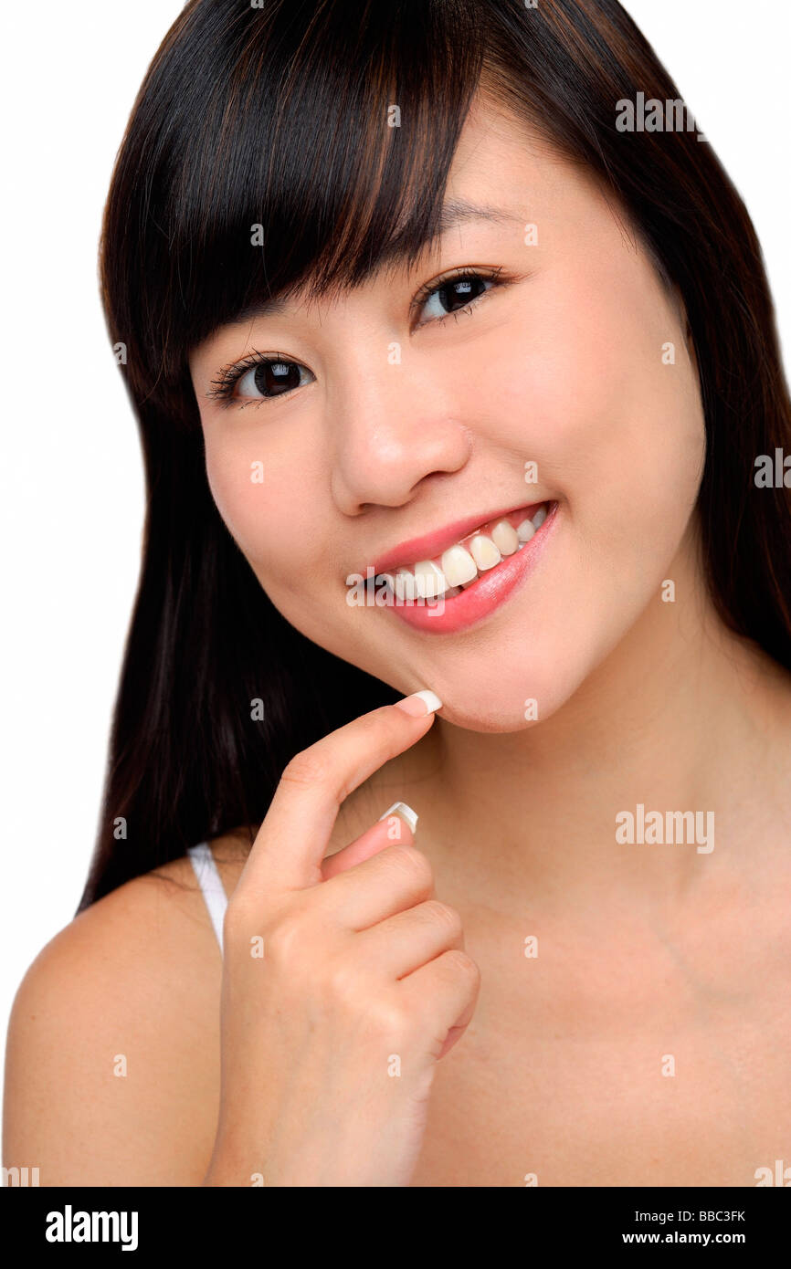 Young woman smiling, finger to chin, portrait Stock Photo - Alamy