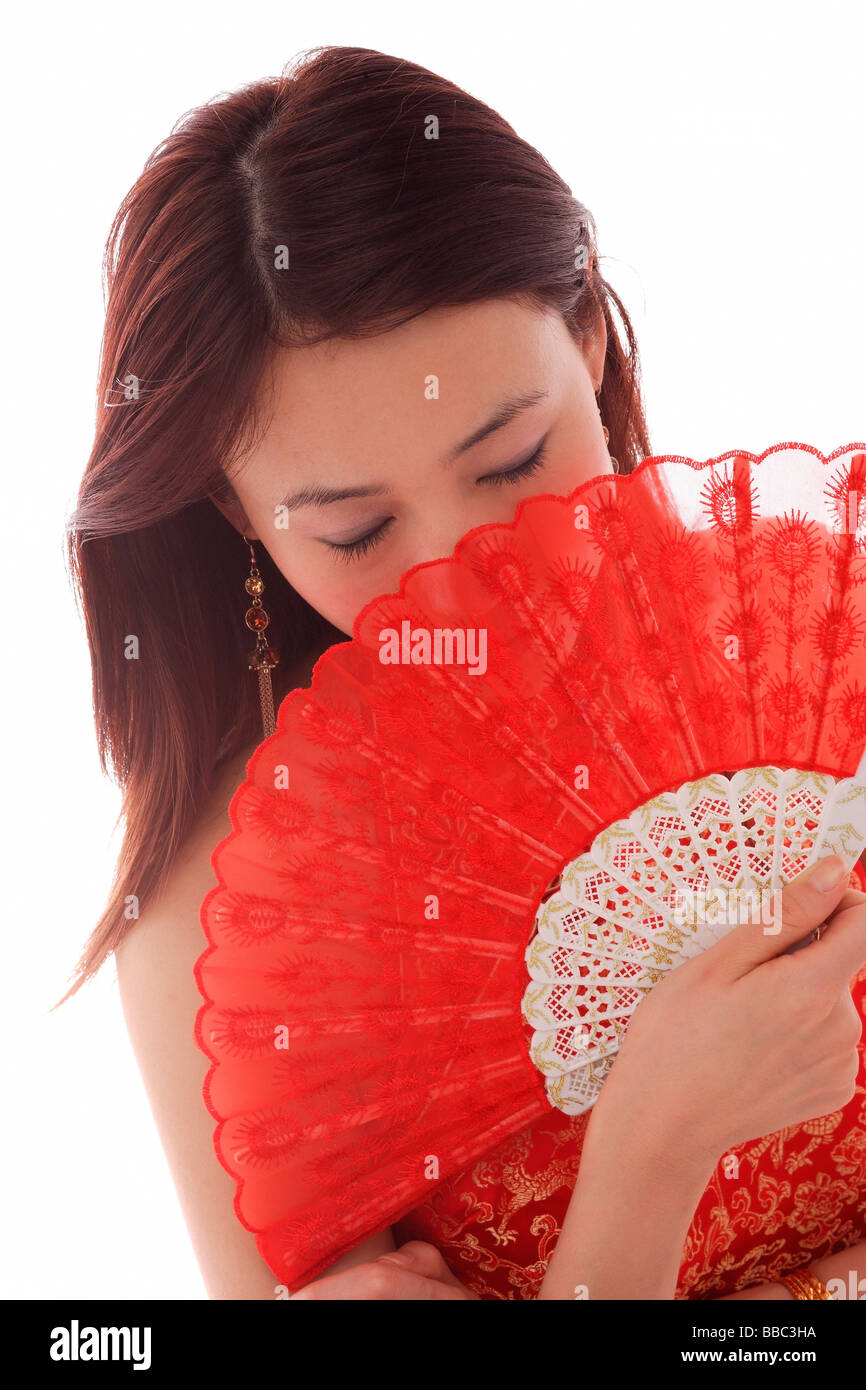 Young woman holding fan in front of face Stock Photo - Alamy
