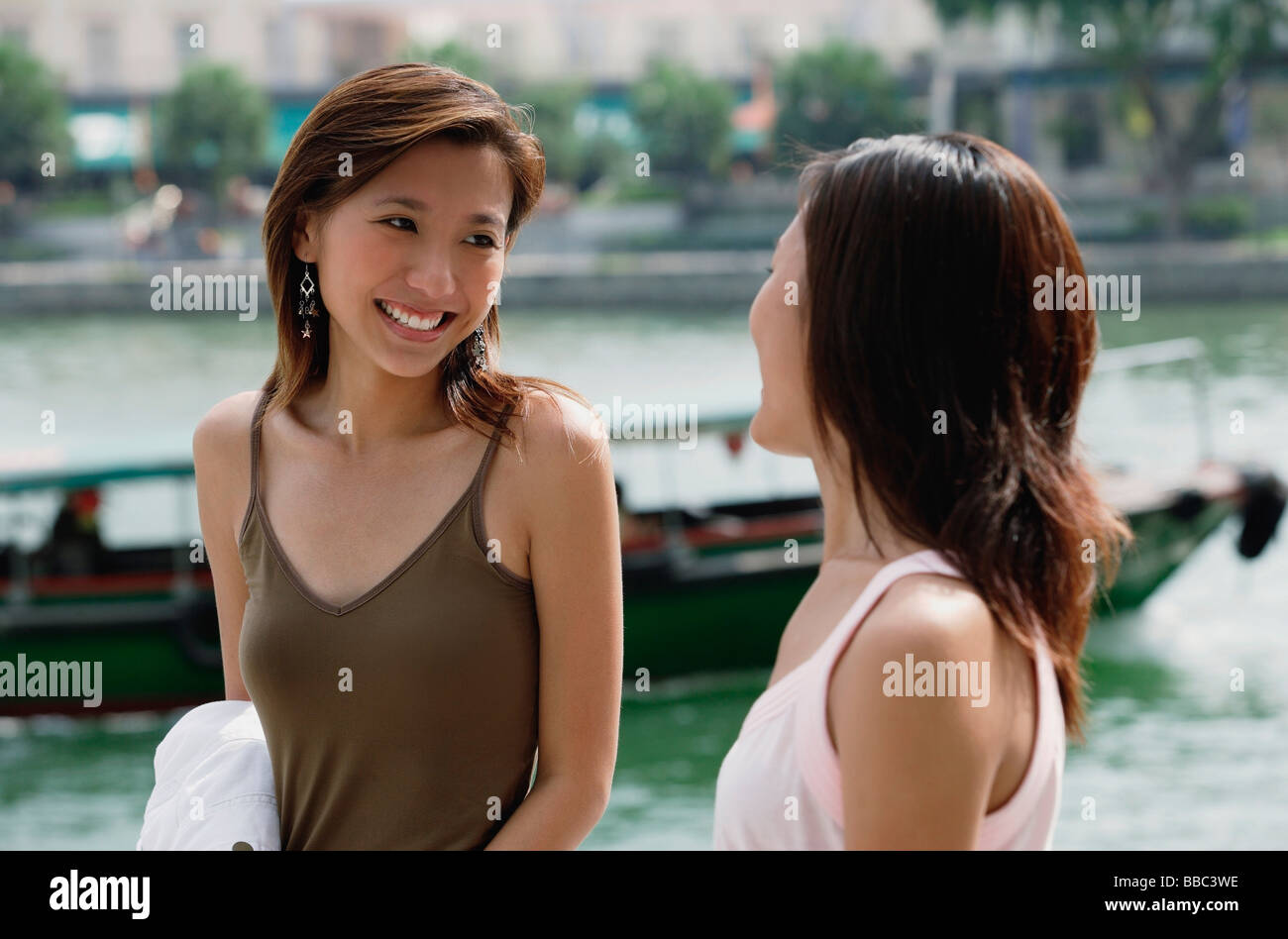 Two women smiling at each other, river behind them Stock Photo - Alamy