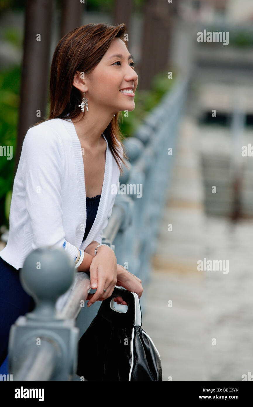 Woman leaning on railing, looking away Stock Photo - Alamy