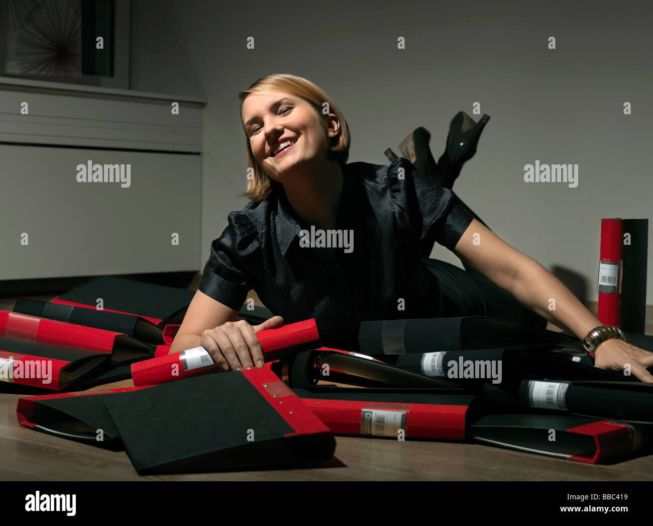 Woman laying in pile of binders Stock Photo - Alamy