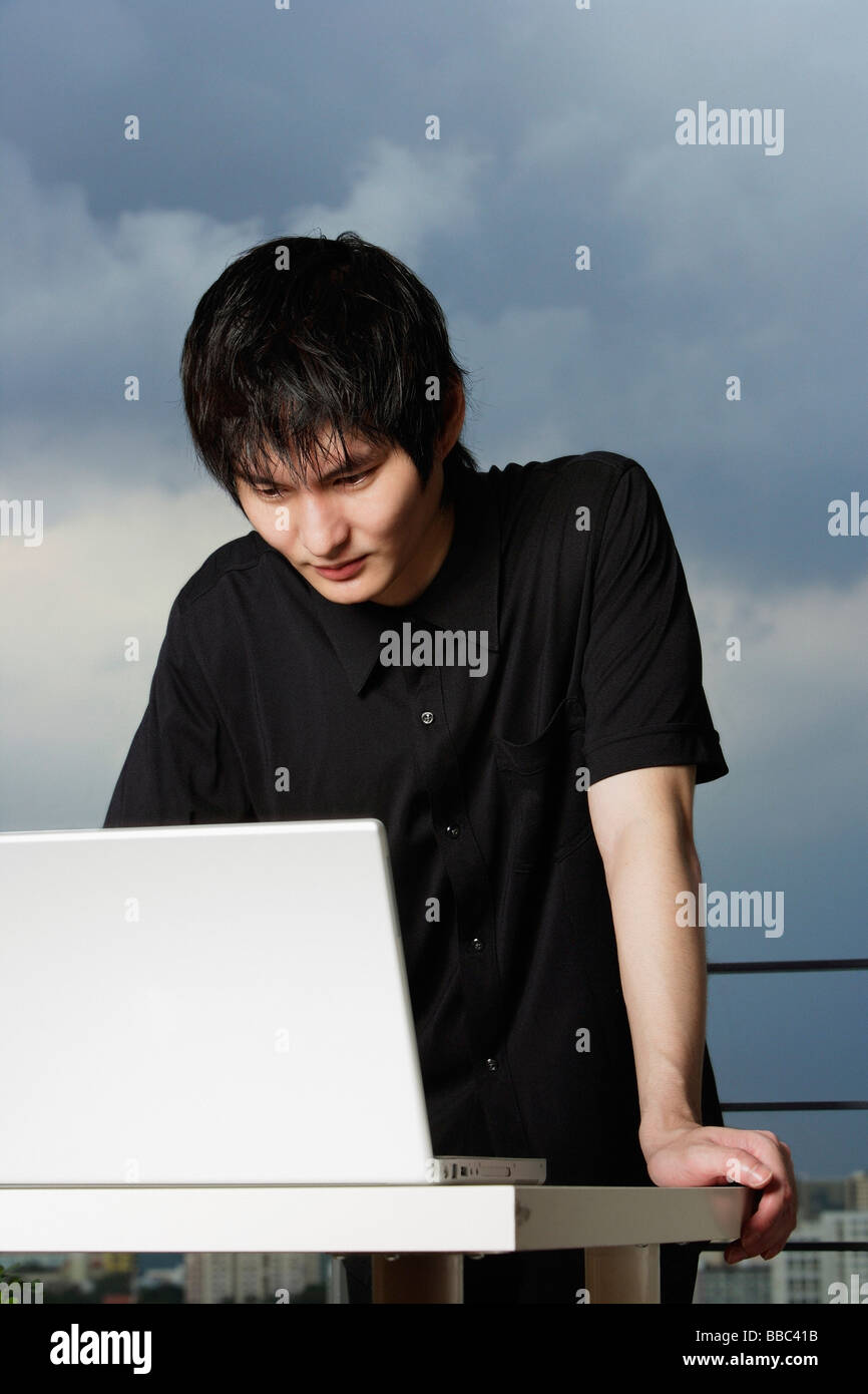 young man standing, using laptop Stock Photo - Alamy