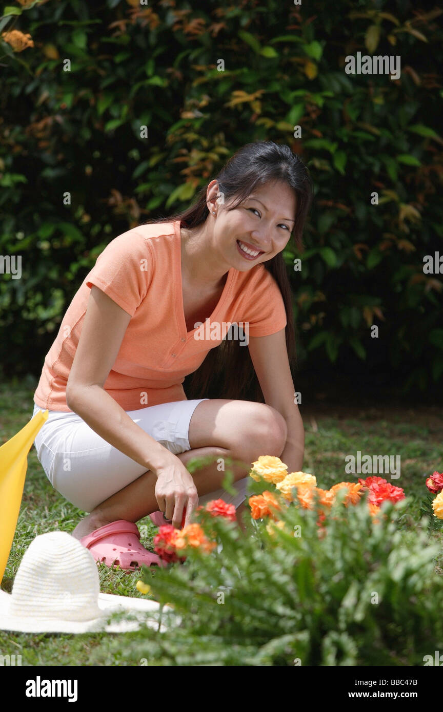 Woman tending to flower bed in garden Stock Photo - Alamy
