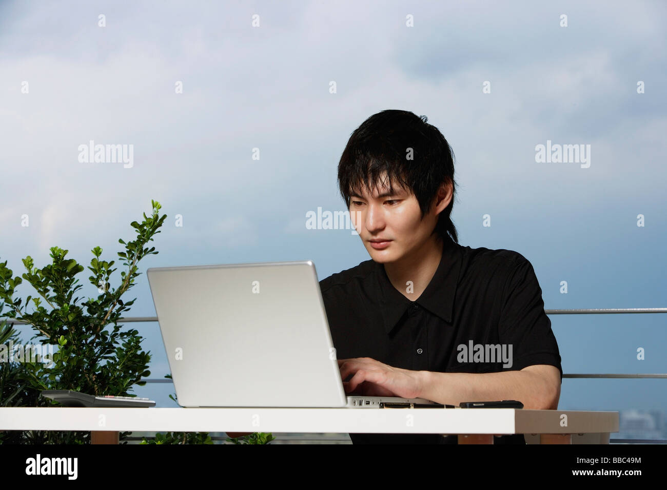 young man sitting outdoor using laptop Stock Photo - Alamy