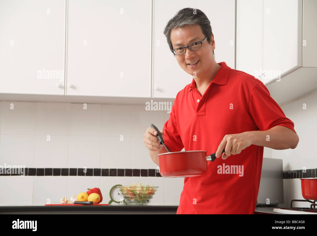 Man in kitchen cooking with sauce pan, looking at camera Stock Photo ...