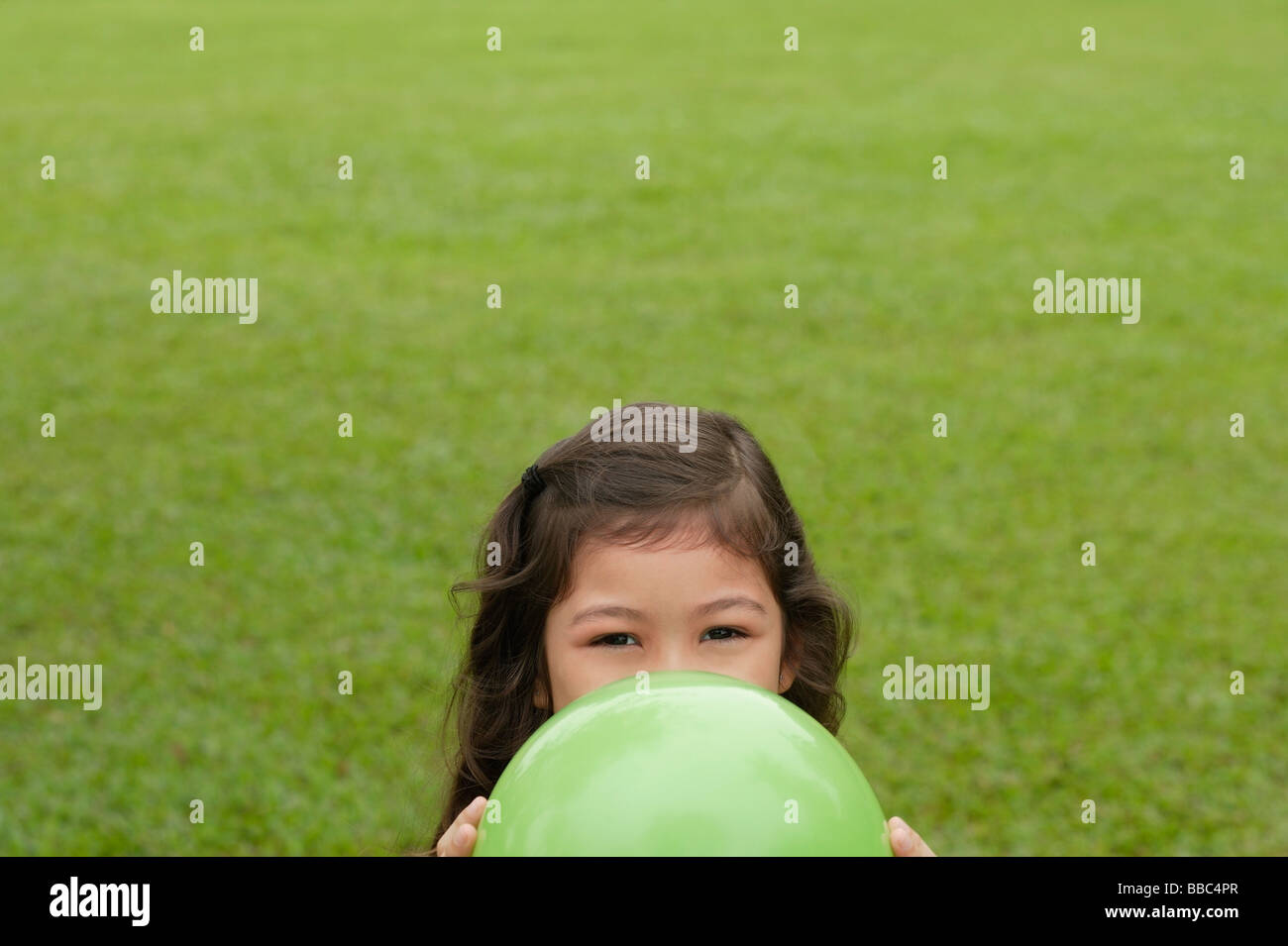 Girl hiding behind green balloon Stock Photo - Alamy