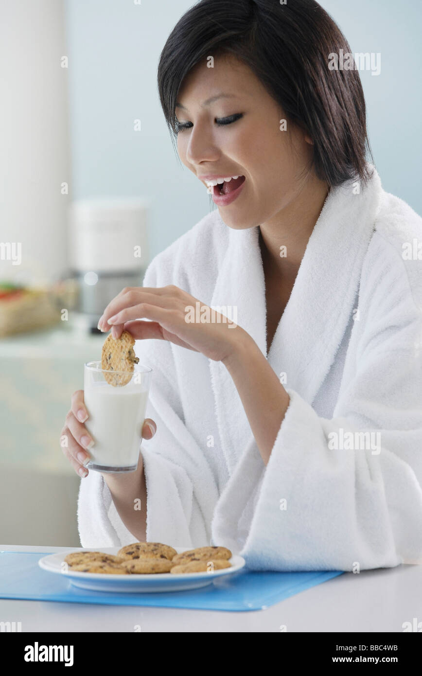 woman in kitchen, dipping cooking in glass of milk, smiling Stock Photo ...