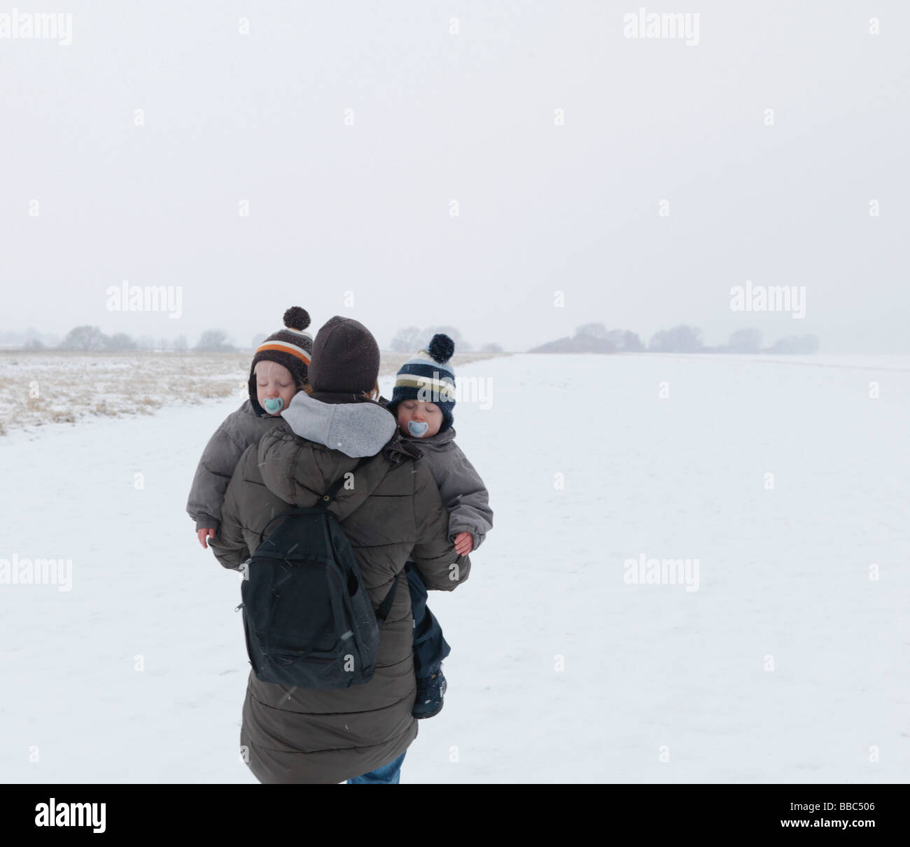 Woman walking with twin sons in snow Stock Photo - Alamy