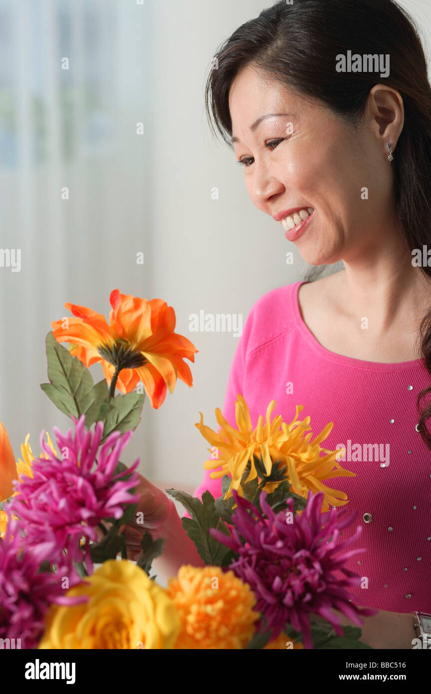 Mature woman looking at flowers, smiling Stock Photo - Alamy
