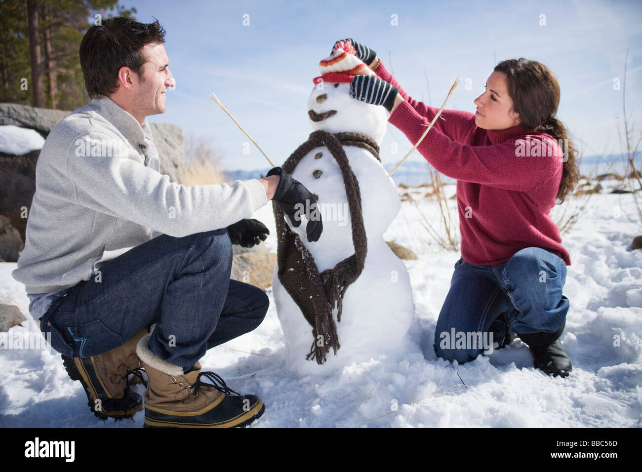 Couple building snowman Stock Photo - Alamy