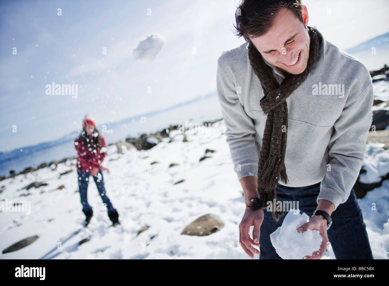 Woman throwing snowball at man Stock Photo - Alamy