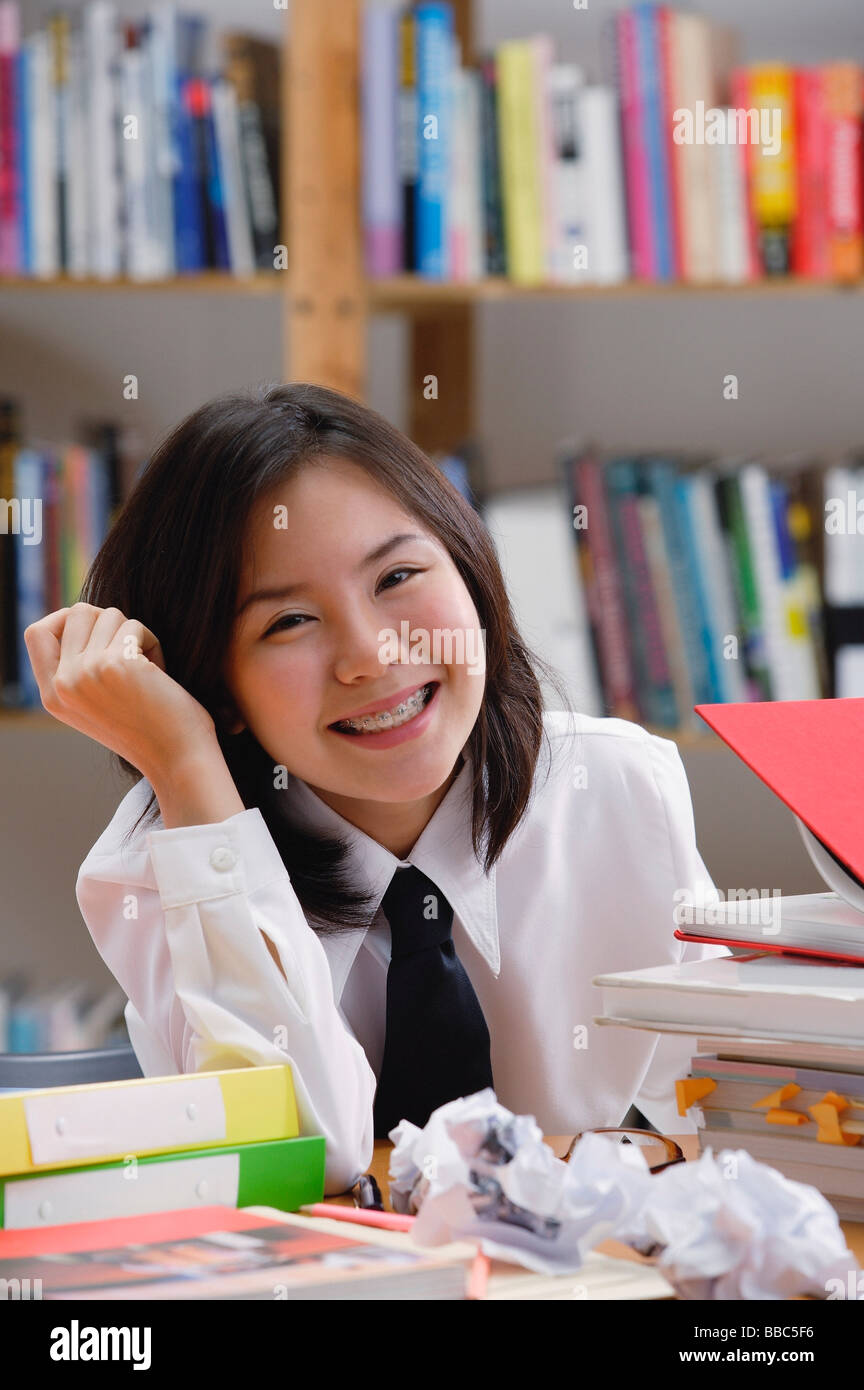 Young woman in library, surrounded by books and crumpled paper Stock ...