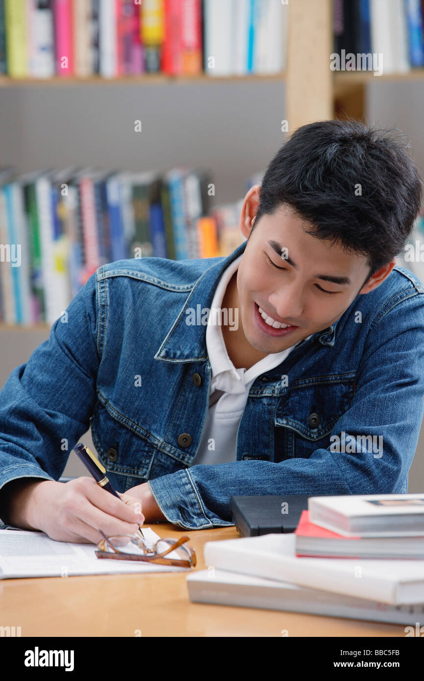 Young man in library, writing Stock Photo - Alamy