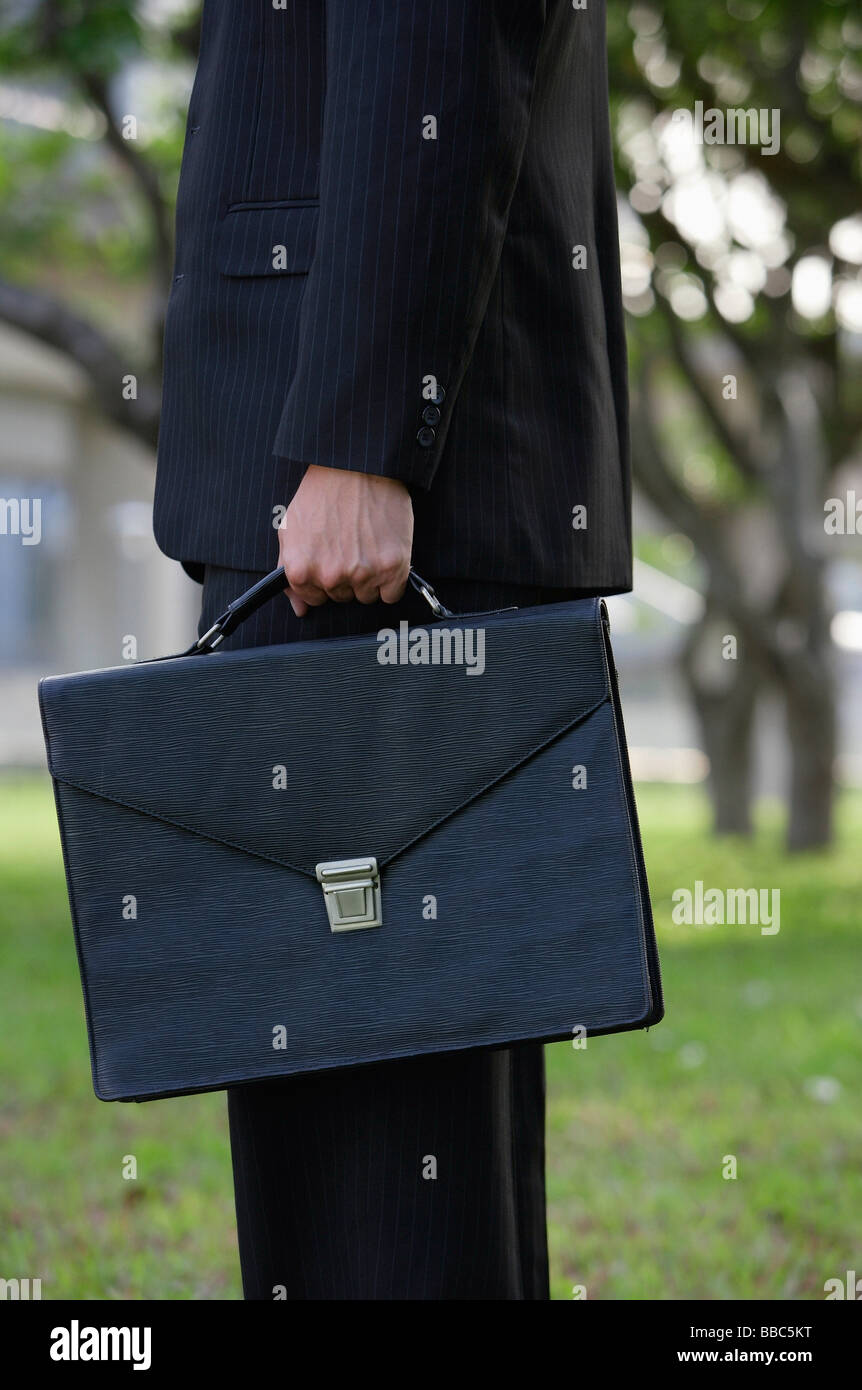 Businessman holding briefcase, side view Stock Photo - Alamy