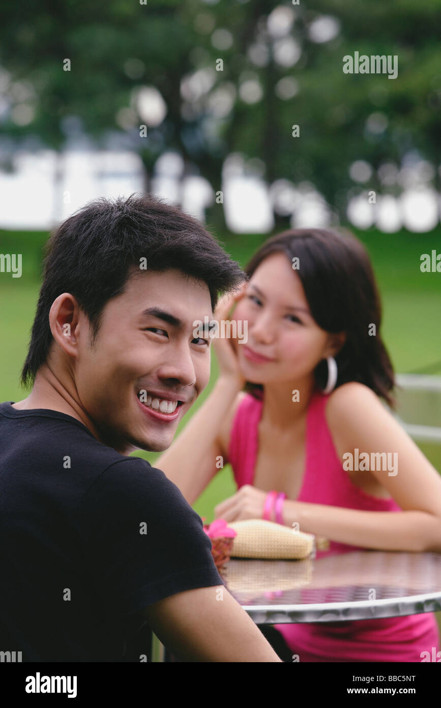 Man turning to smile at camera, woman in the background Stock Photo - Alamy