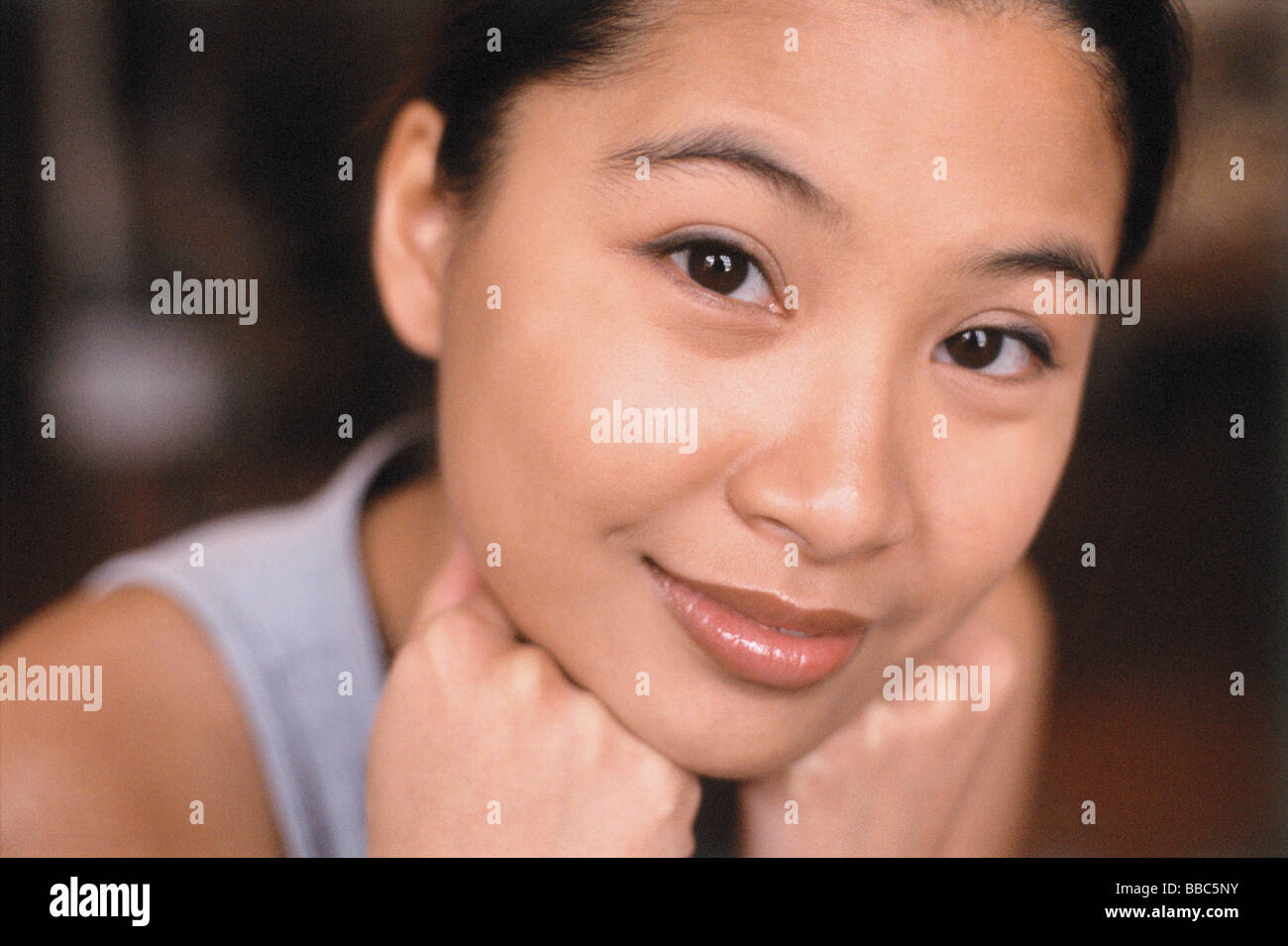 Young woman with hands on chin, smiling Stock Photo - Alamy