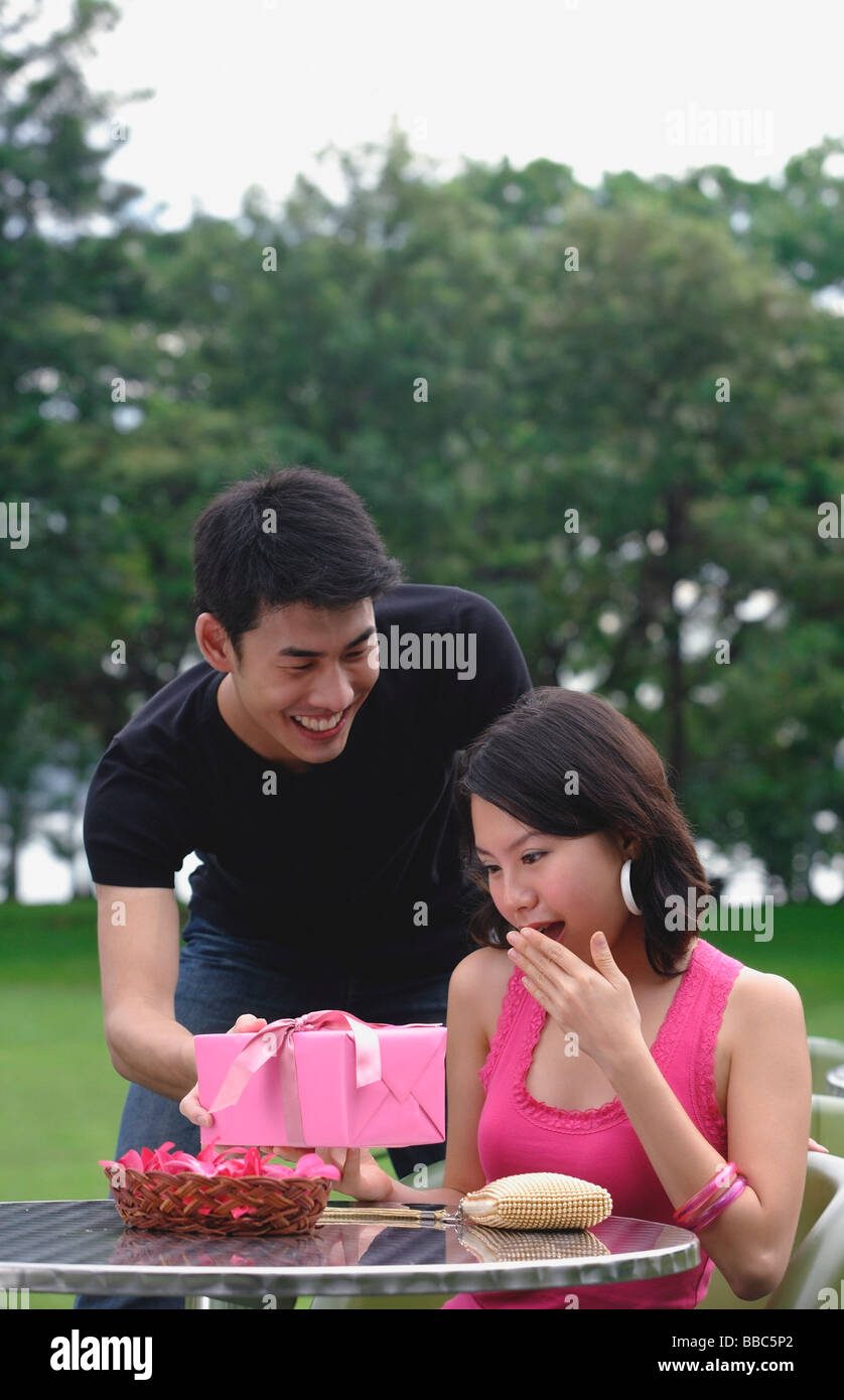 Man surprising woman with gift Stock Photo - Alamy