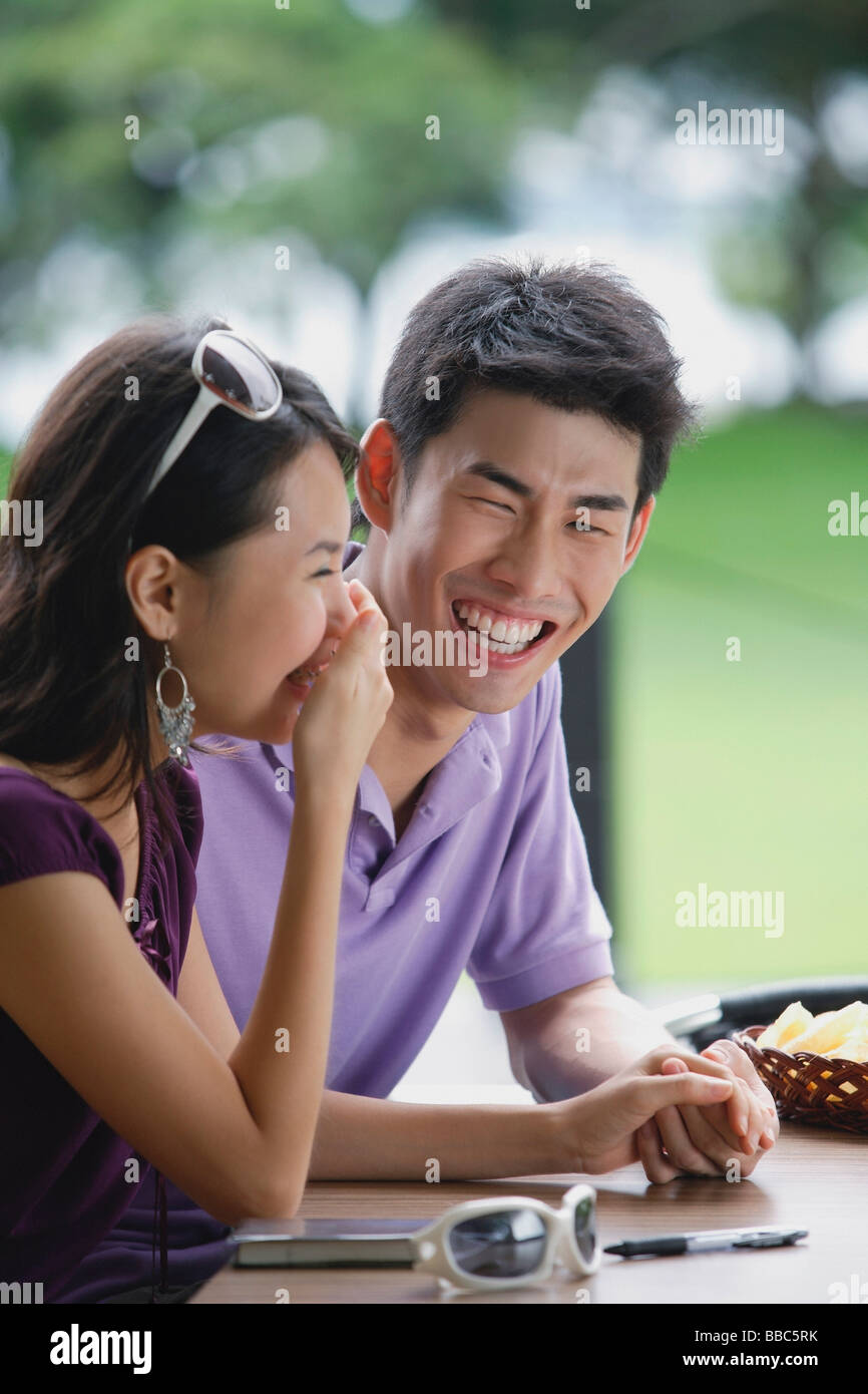 Couple sitting at cafe, young woman with hand over mouth, smiling Stock ...