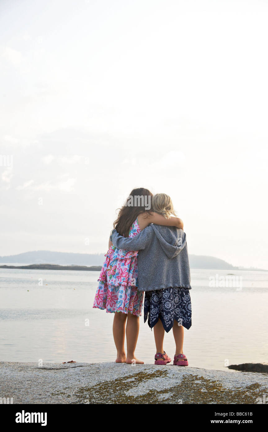 Two girls arm in arm by coastline Stock Photo - Alamy