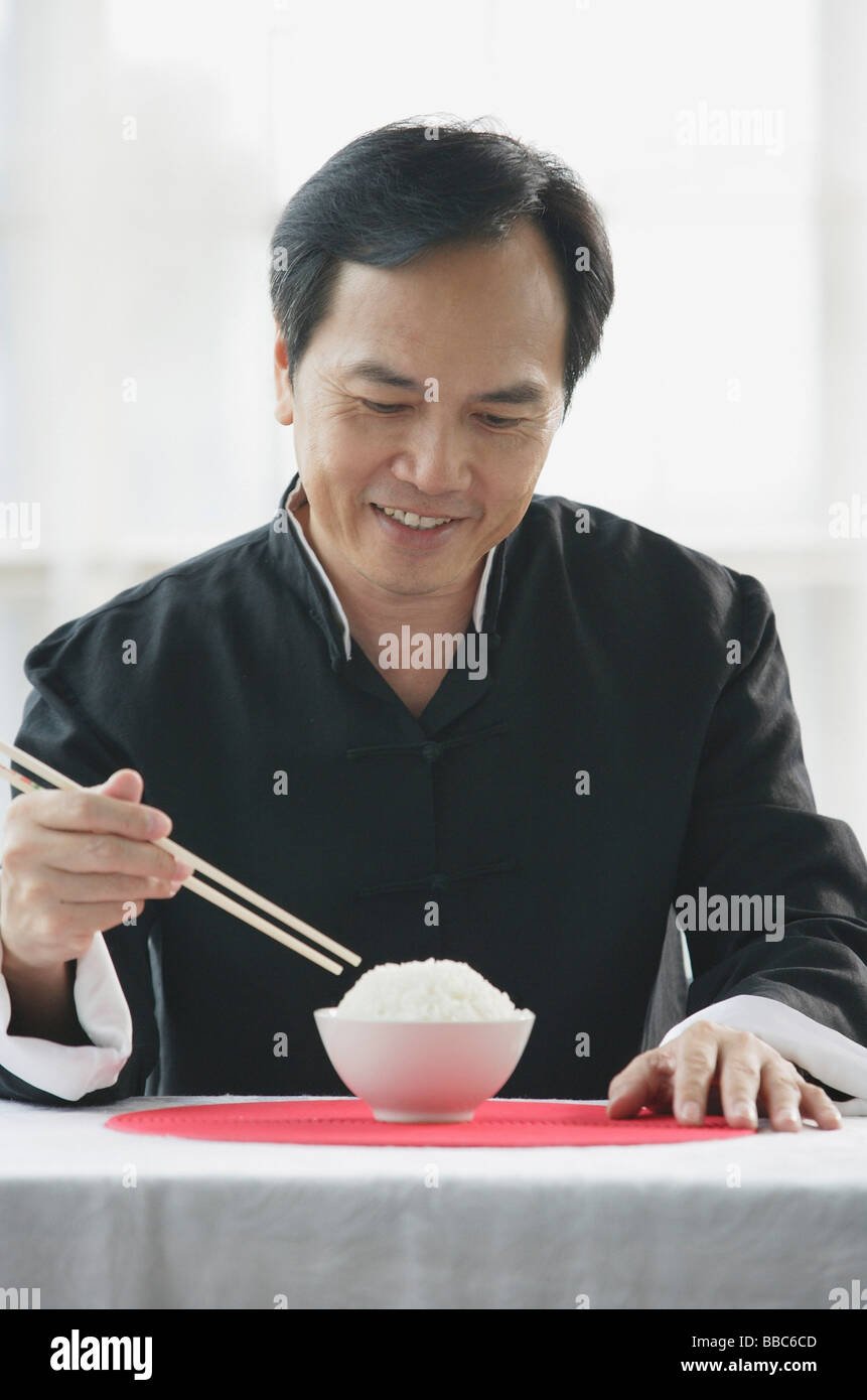 Man looking at bowl of rice on table, holding chopsticks Stock Photo ...