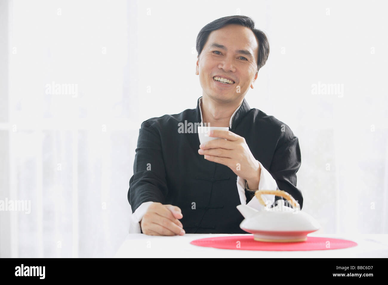 Man holding teacup, smiling at camera Stock Photo - Alamy