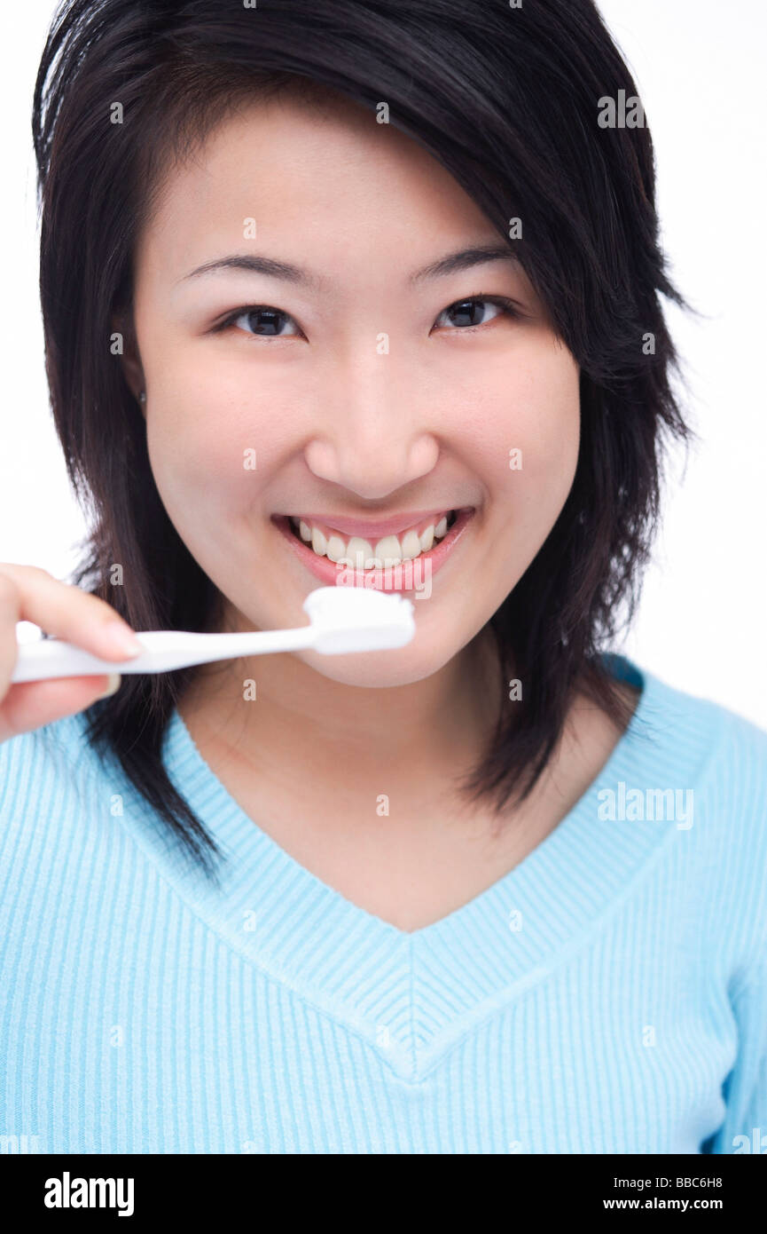 Young woman brushing teeth, smiling at camera Stock Photo - Alamy