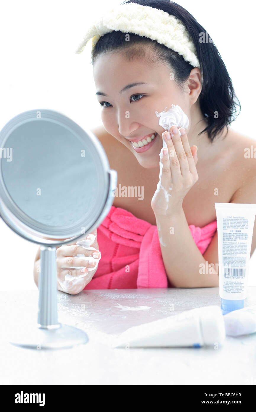 Young woman sitting at dressing table, putting lotion on face Stock ...