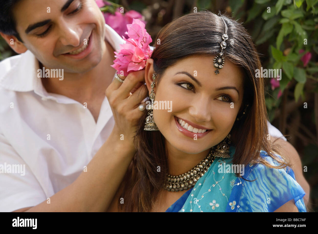 young man putting flowers behind young woman's ear Stock Photo - Alamy