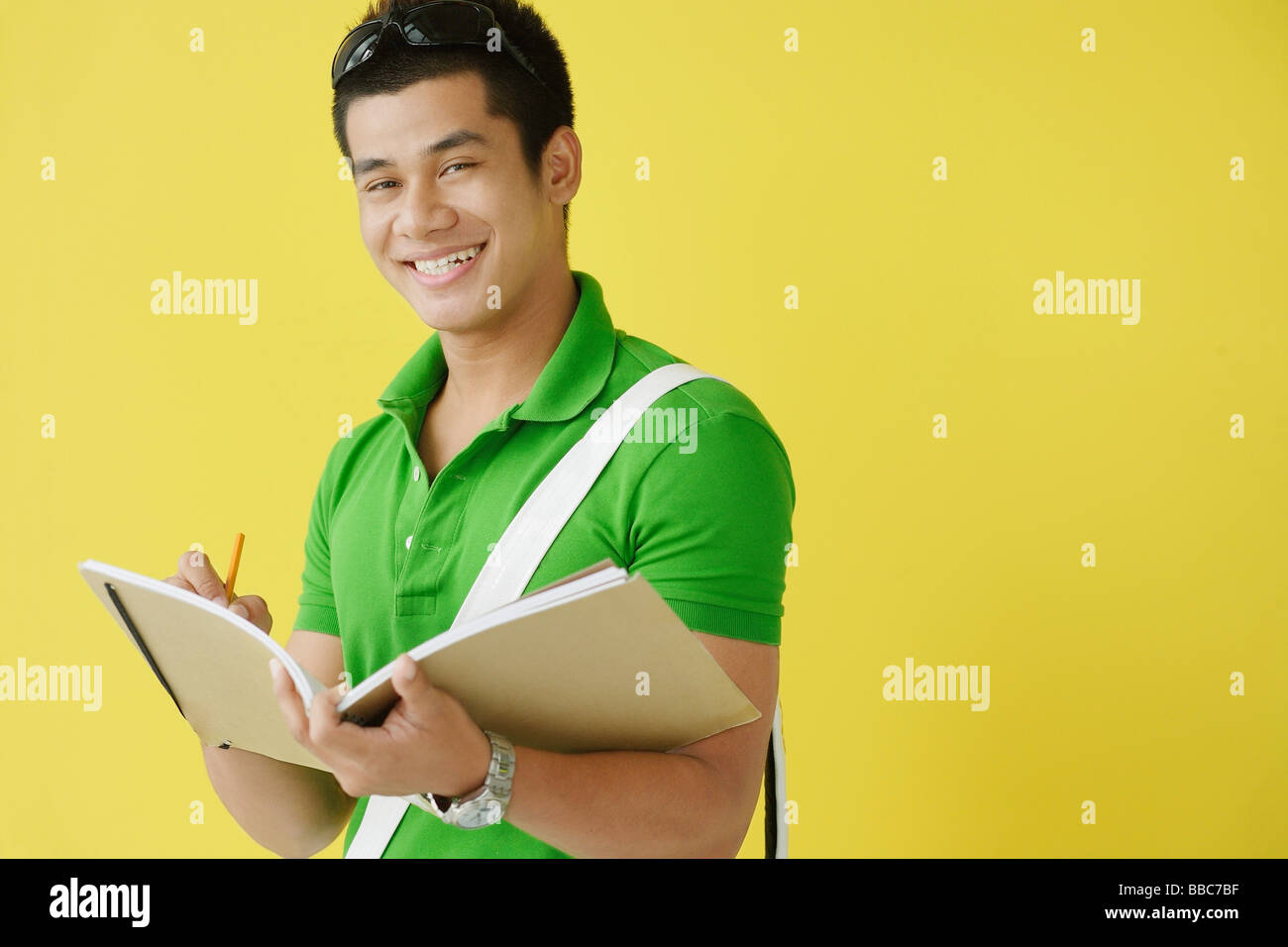 Young man writing in notebook, looking at camera Stock Photo - Alamy