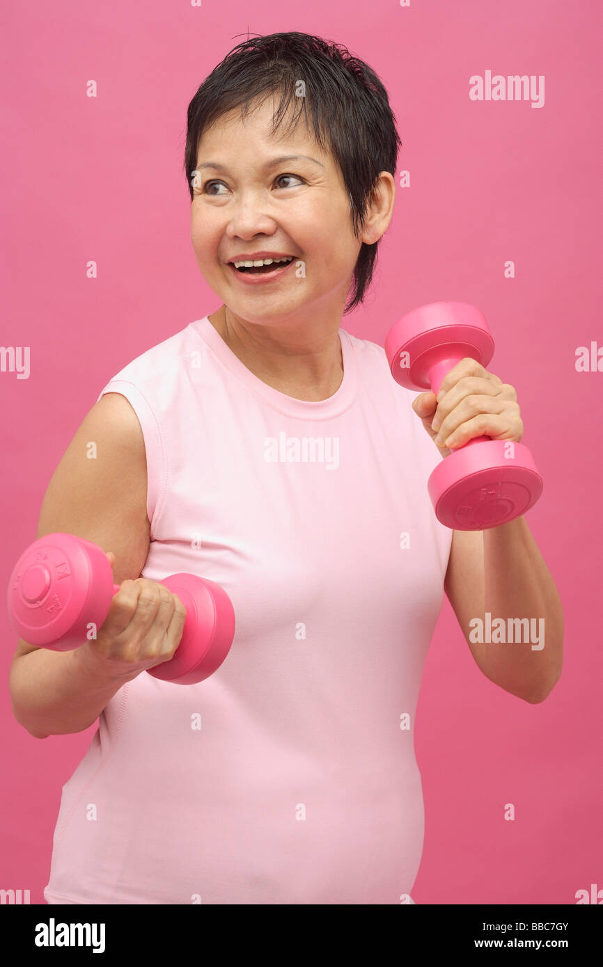 Mature woman using dumbbells Stock Photo - Alamy