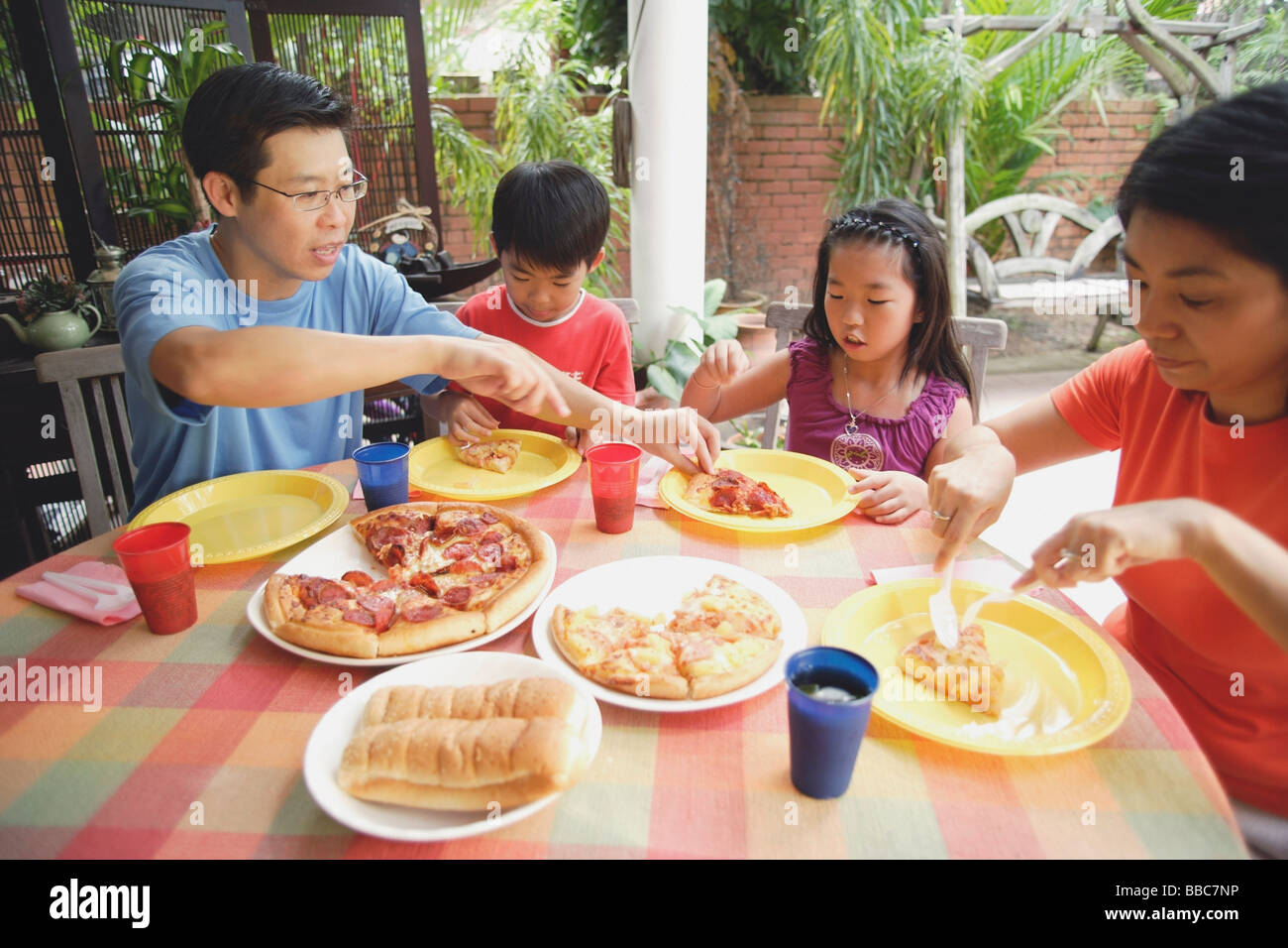 Family of four having pizza on patio Stock Photo - Alamy