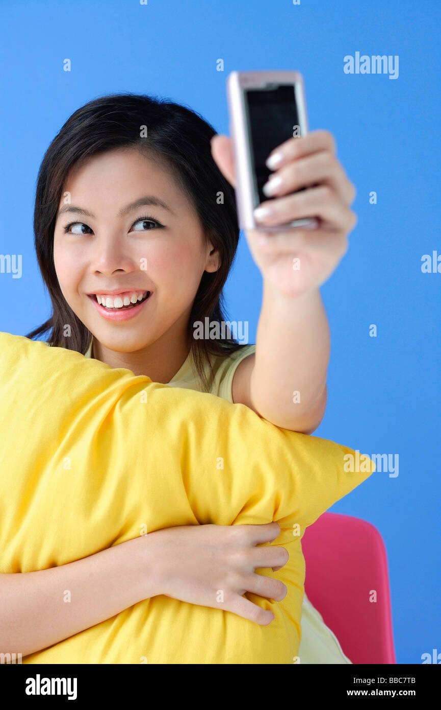 Young woman hugging pillow, using camera phone Stock Photo - Alamy