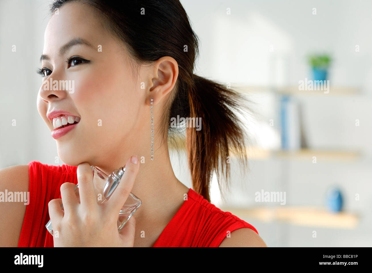 Young woman spraying perfume Stock Photo - Alamy