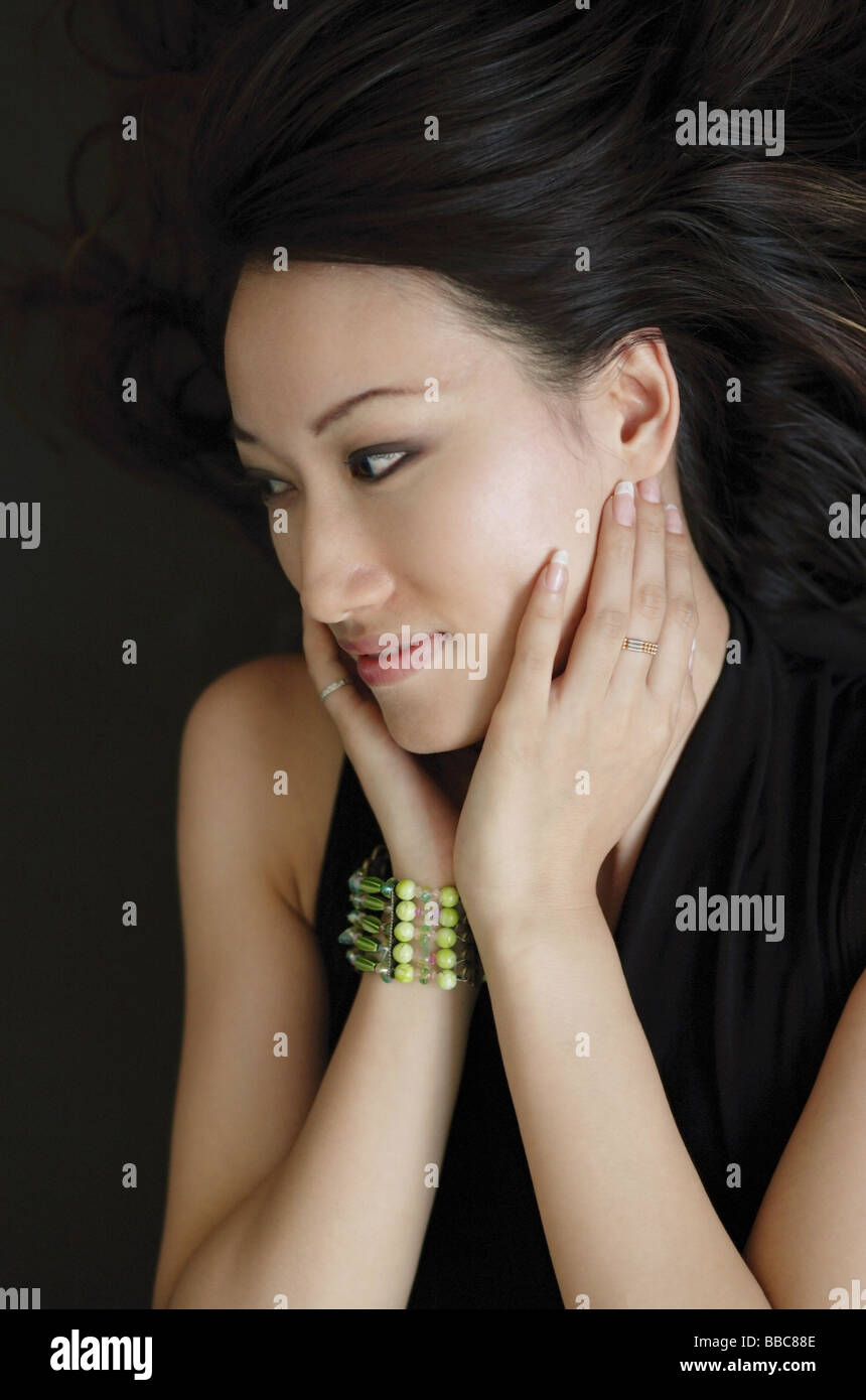 Woman with hands on face, looking away Stock Photo - Alamy