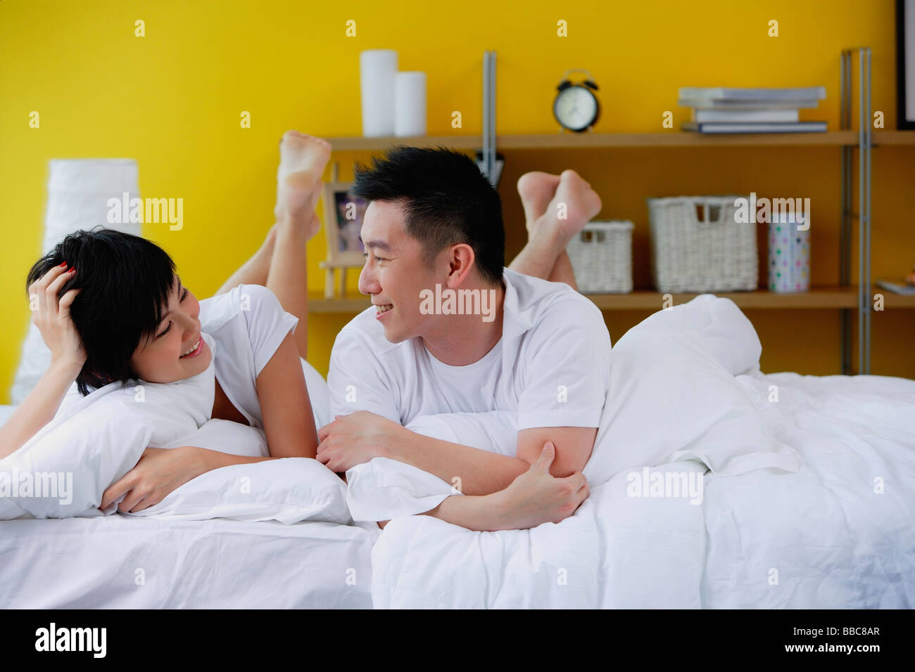 Couple lying on bed, smiling at each other Stock Photo - Alamy