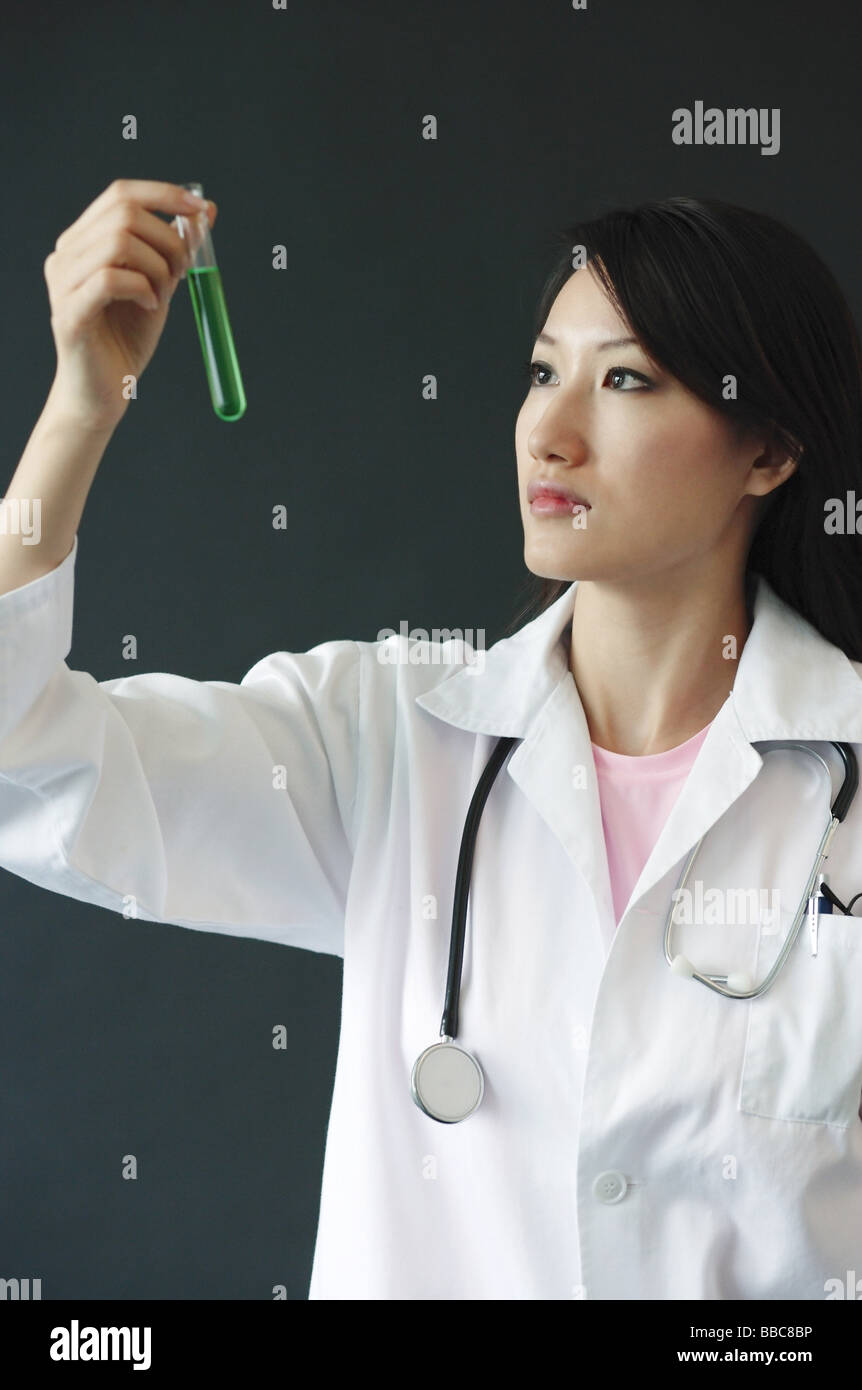 Doctor looking at test tube filled with green liquid Stock Photo - Alamy