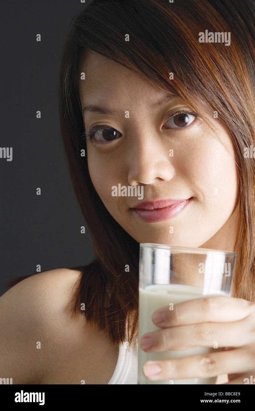Young woman holding glass of milk, looking at camera Stock Photo - Alamy