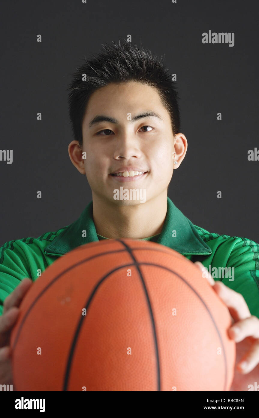 Young man holding basketball, looking at camera Stock Photo - Alamy