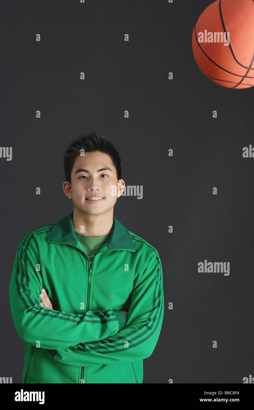 Young man in green jacket, arms crossed, basketball in the air Stock ...