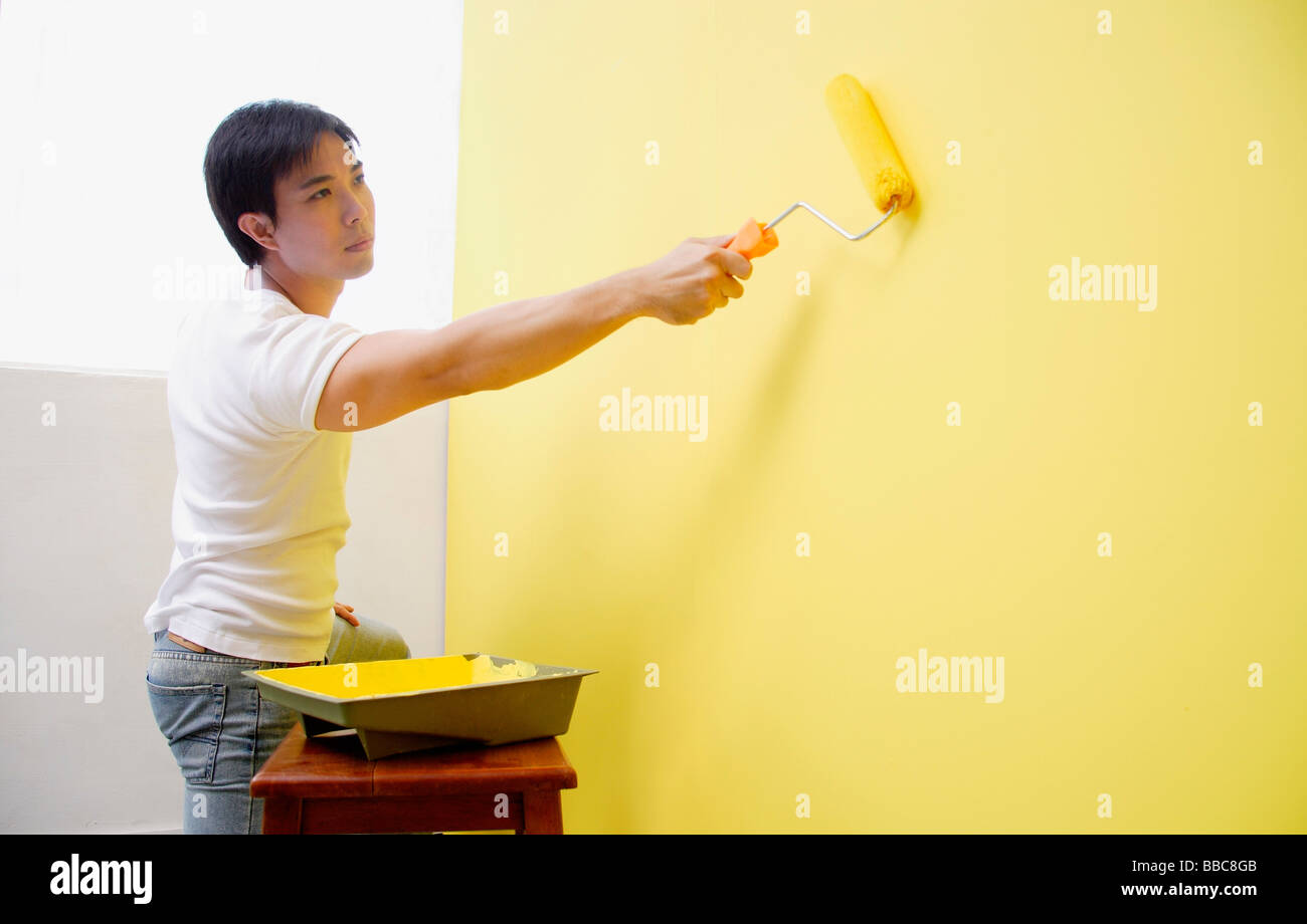 Man painting wall with yellow paint Stock Photo - Alamy