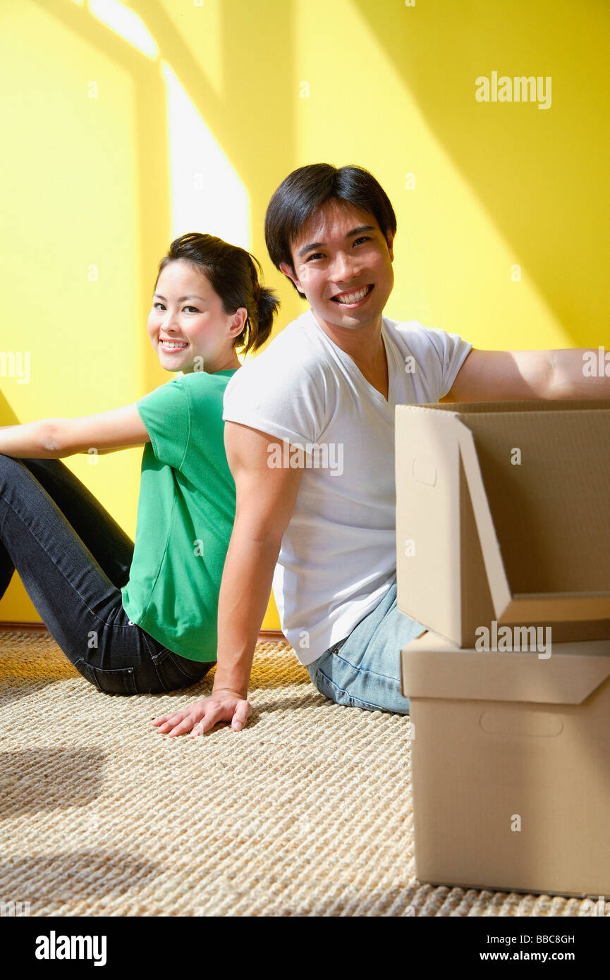 Couple sitting back to back, box open next to them Stock Photo - Alamy